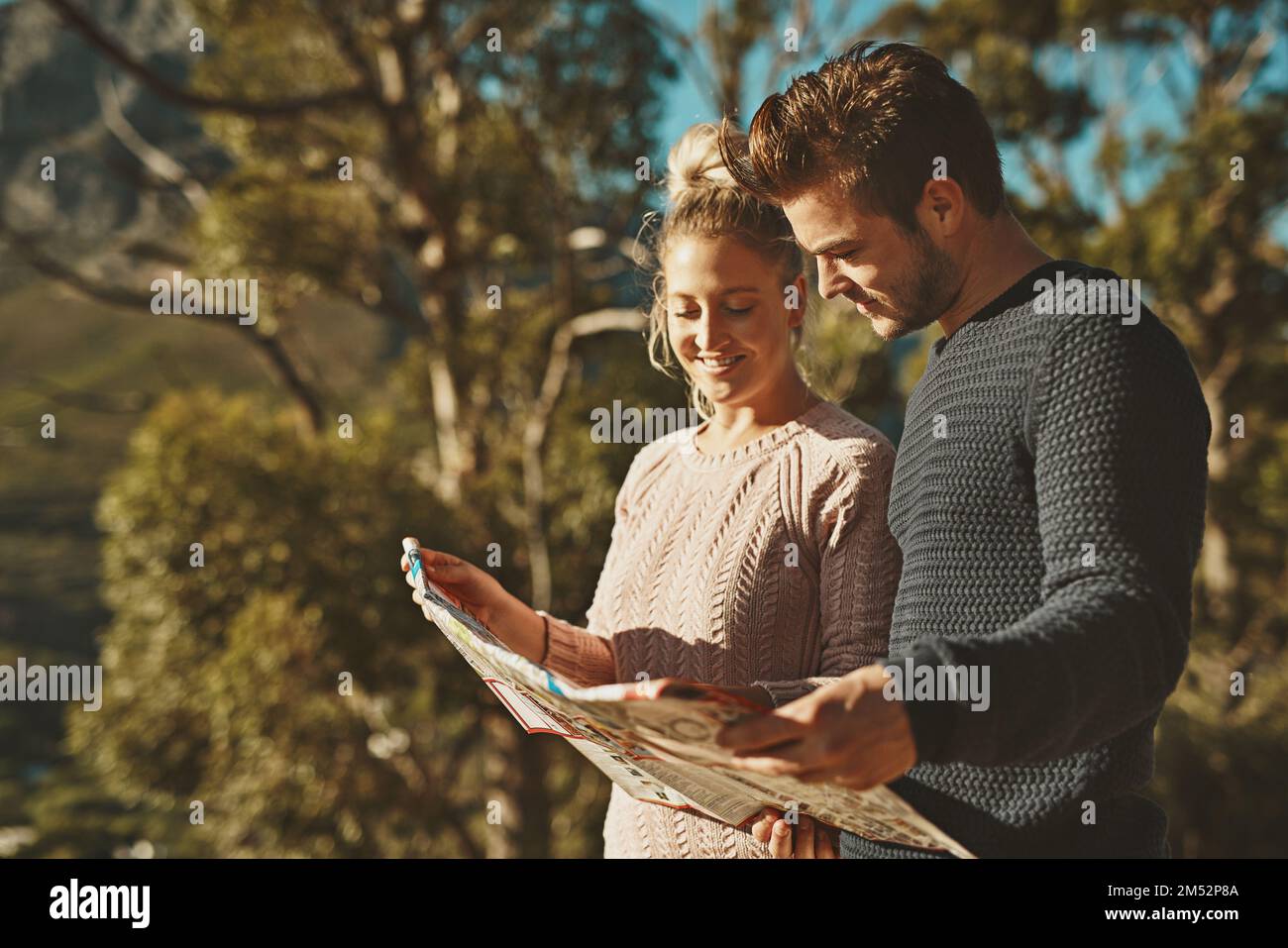 Wherere we heading. a young couple looking at a map while out hiking ...