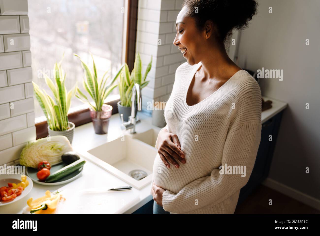 Adult beautiful smiling african pregnant woman holding her belly while ...