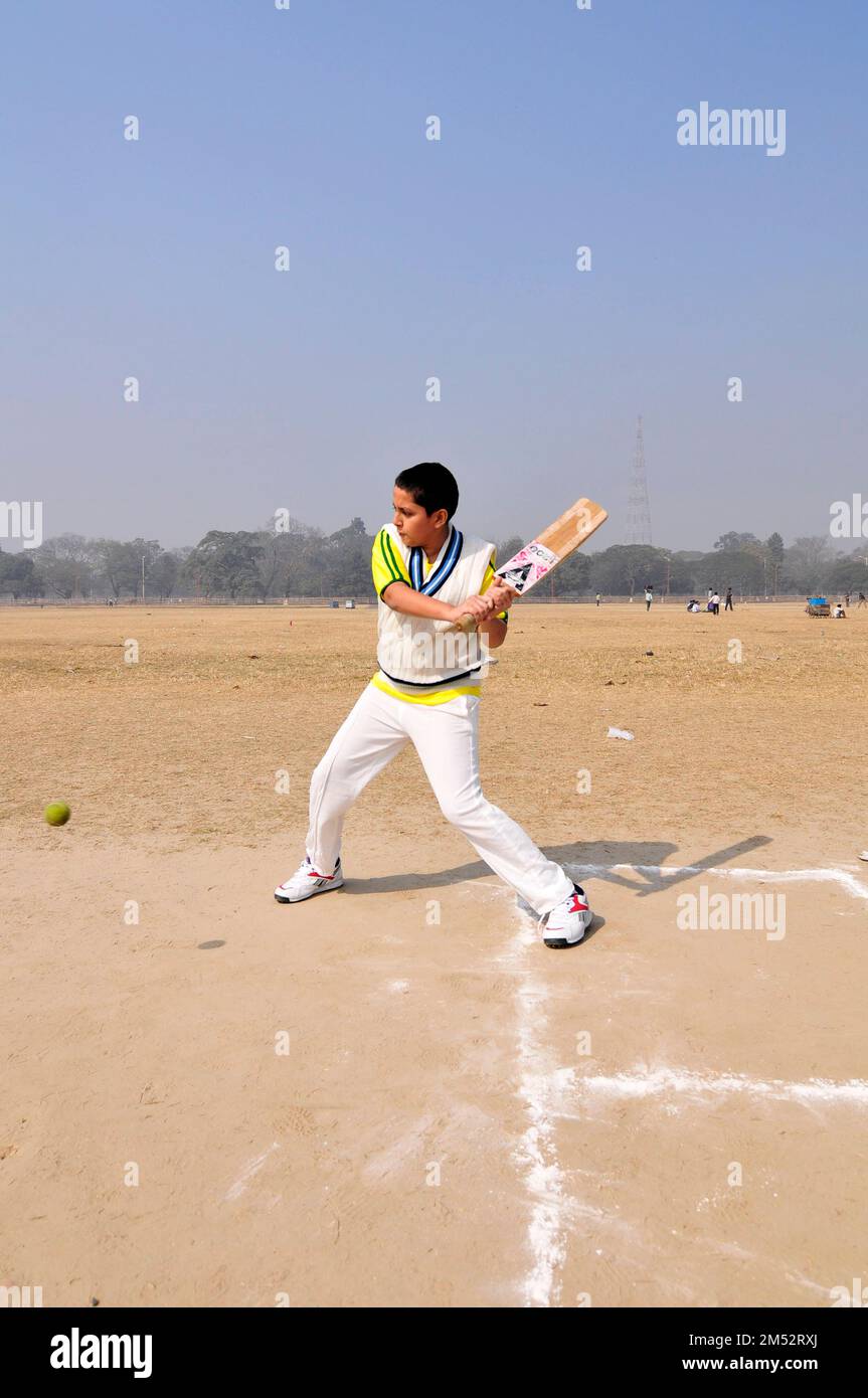 A boy playing Cricket with his friends at the Maidan in Kolkata, West ...