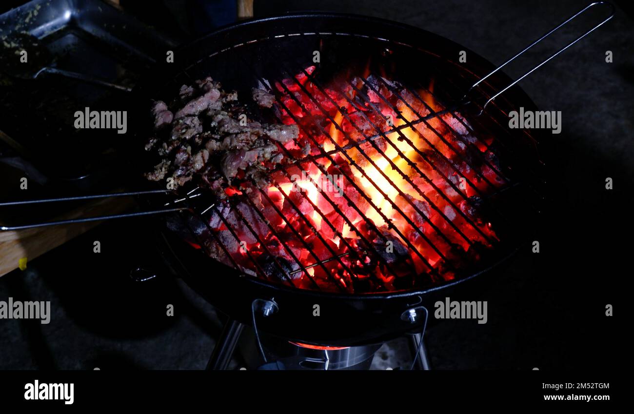 Meat is cooked over coals at barbecue events at night Stock Photo - Alamy
