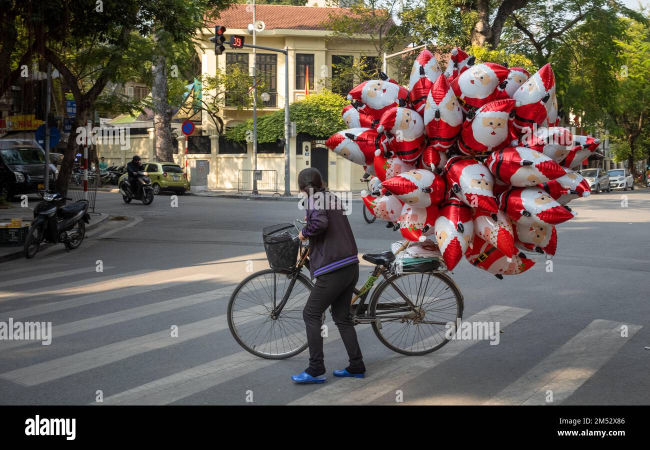 A street vendor pushes her bicycle loaded with father christmas ...
