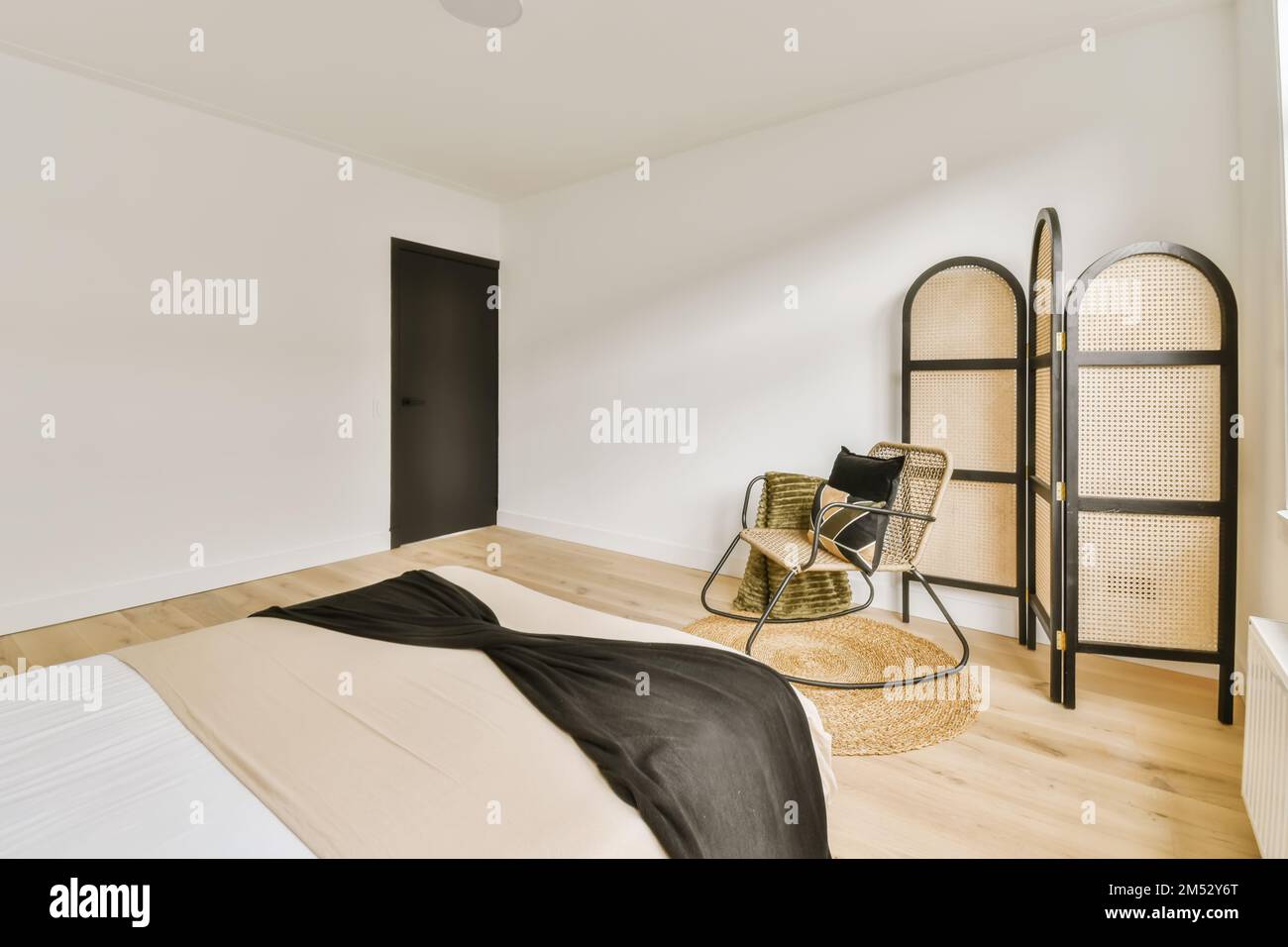 a bedroom with white walls and wood flooring the room is well lit by ...