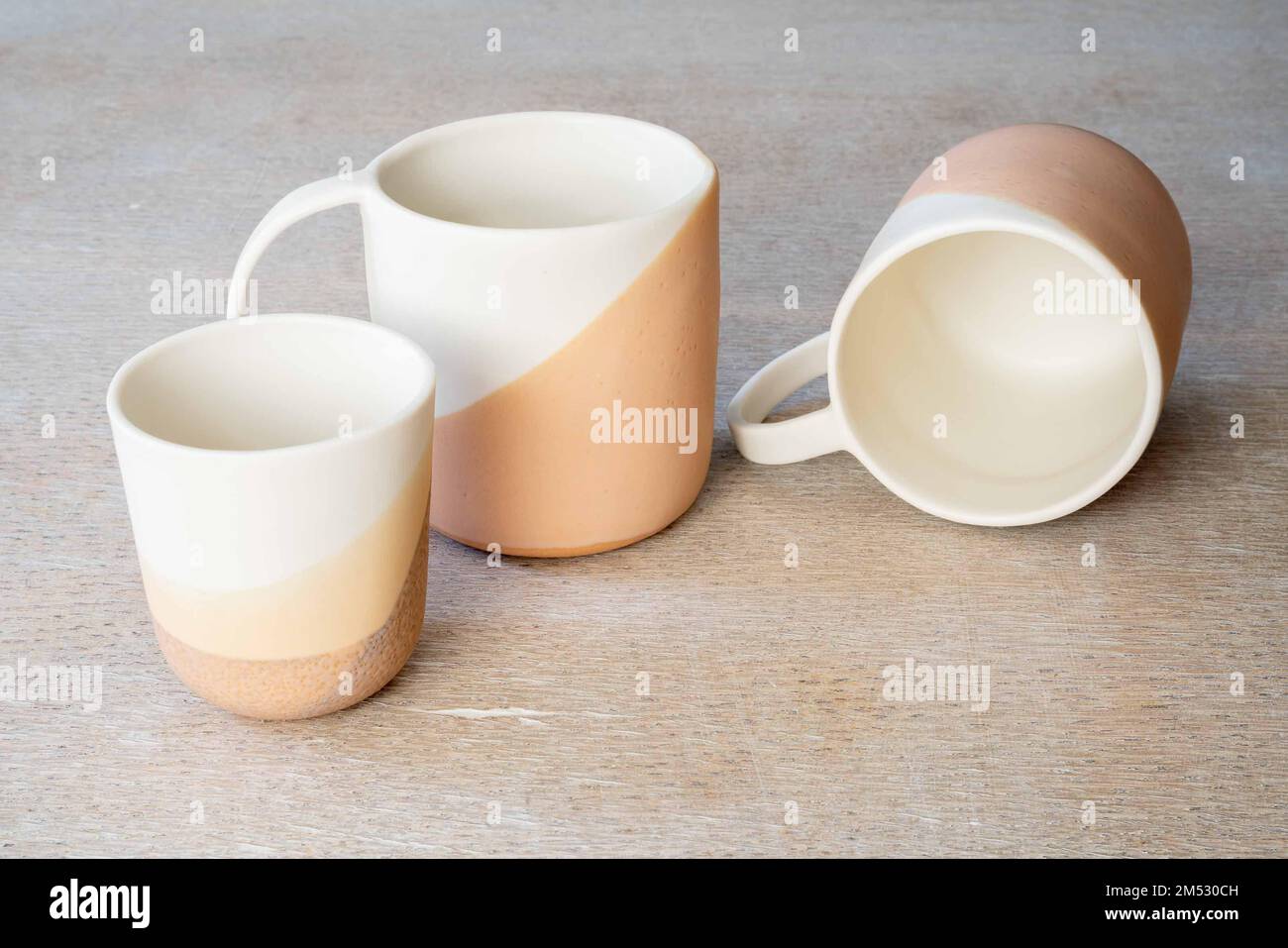 Different sizes of luxury white and brown ceramic dipped mugs on marble ...