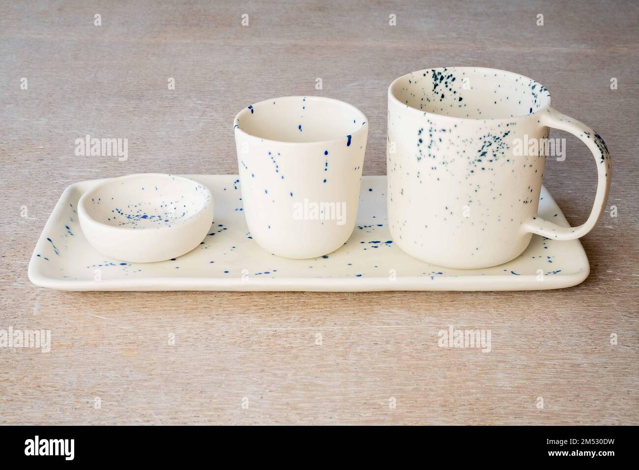 Different sizes of luxury white ceramic dipped mugs on white tray on ...