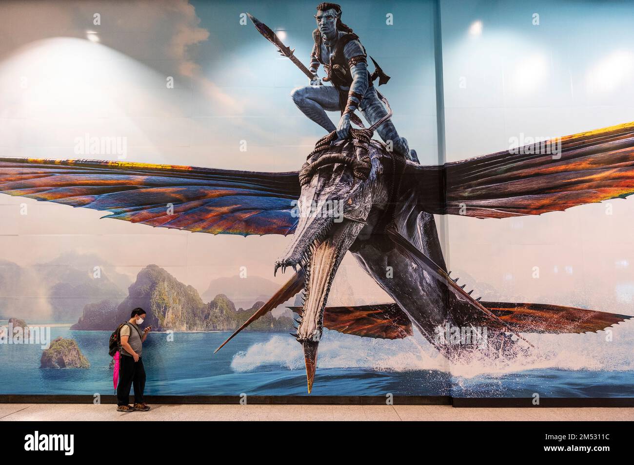 A commuter stands next to a large commercial advertisement banner ...
