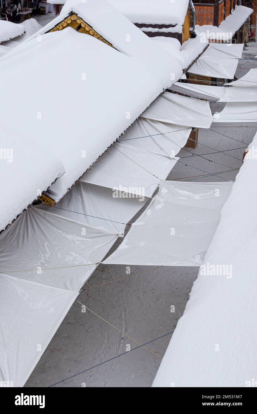 roofs of buildings covered with snow in winter. street market in winter ...