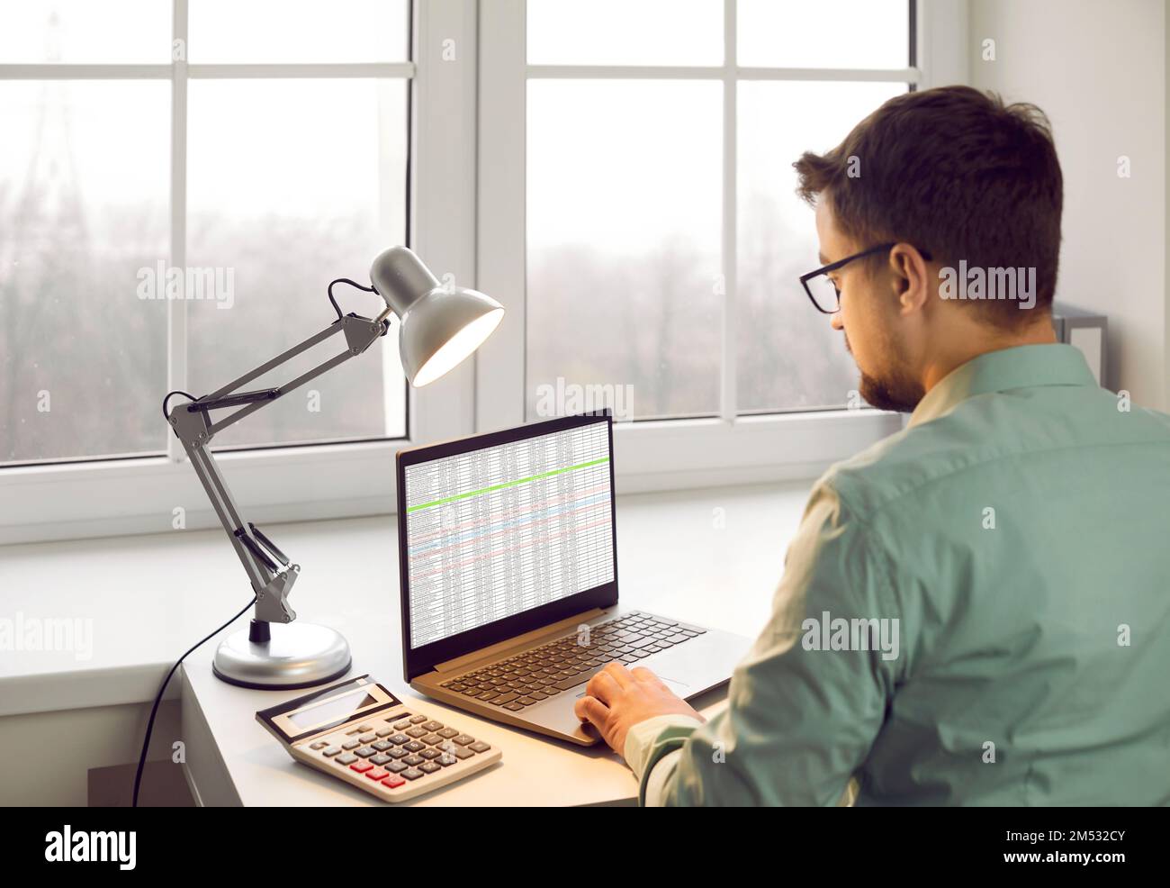 Back of a young businessman working with laptop computer at the office ...