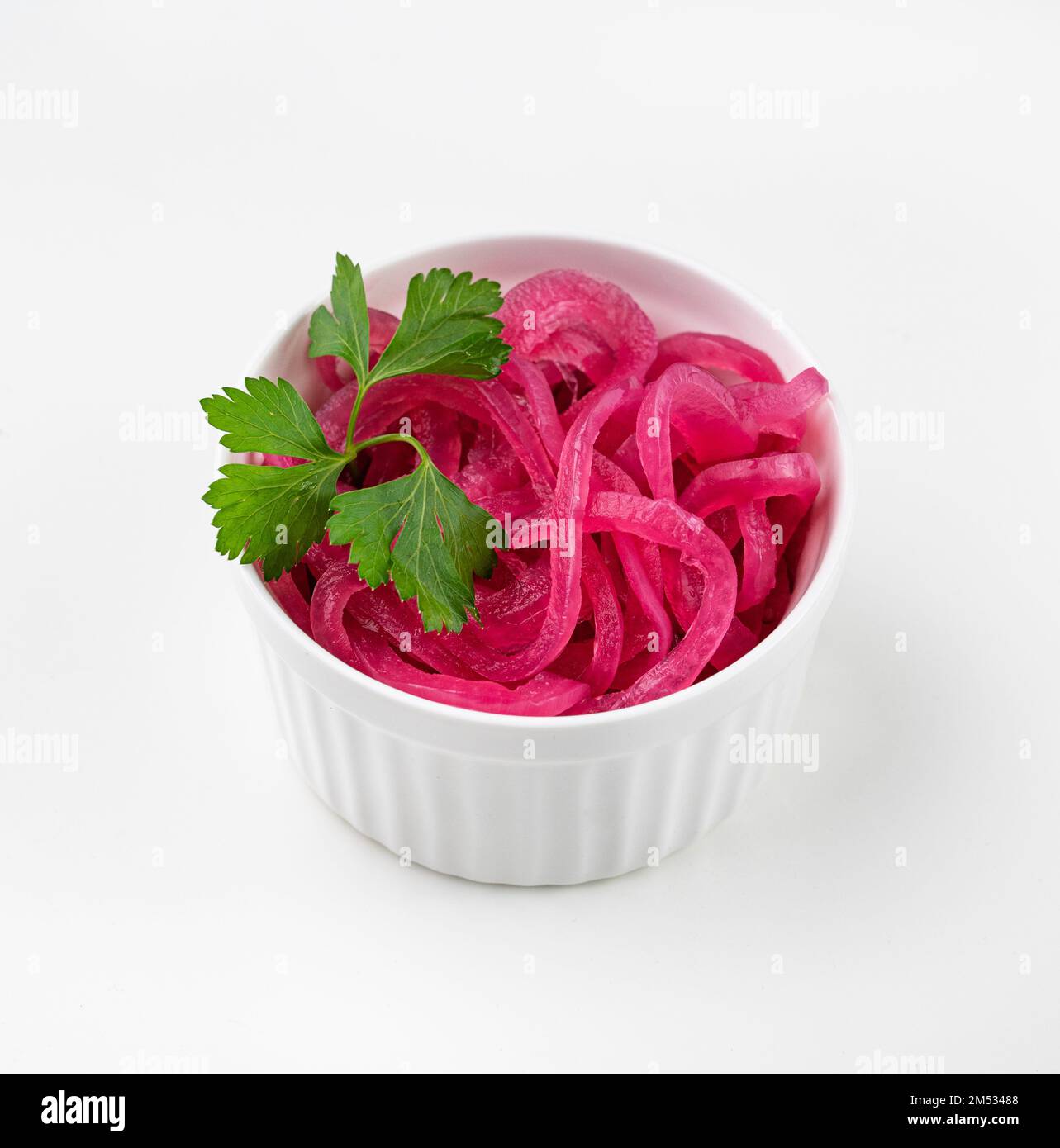 Pickled red onion rings in a bowl with fresh herbs on white background ...