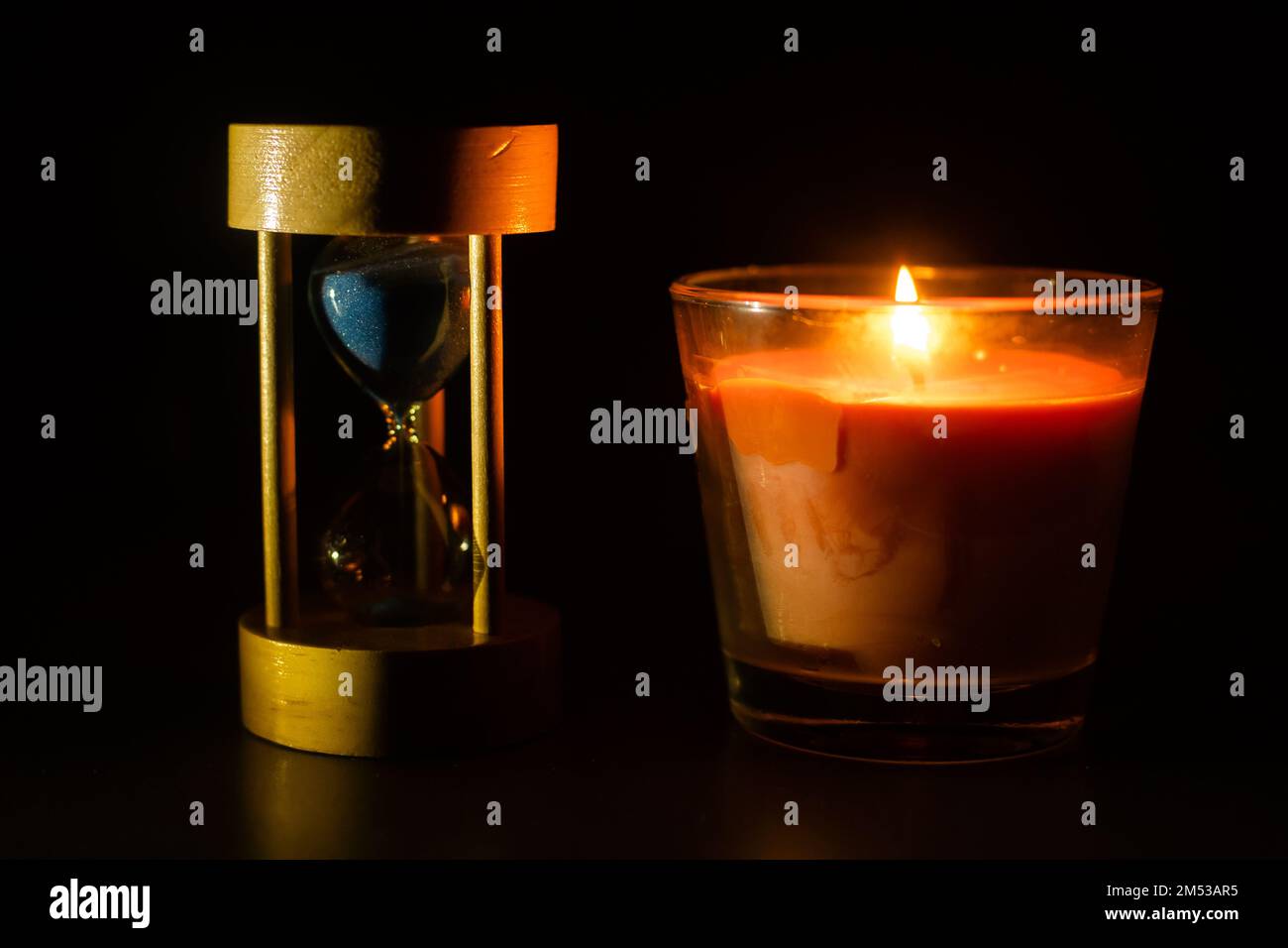 An hourglass under the candle light Stock Photo - Alamy