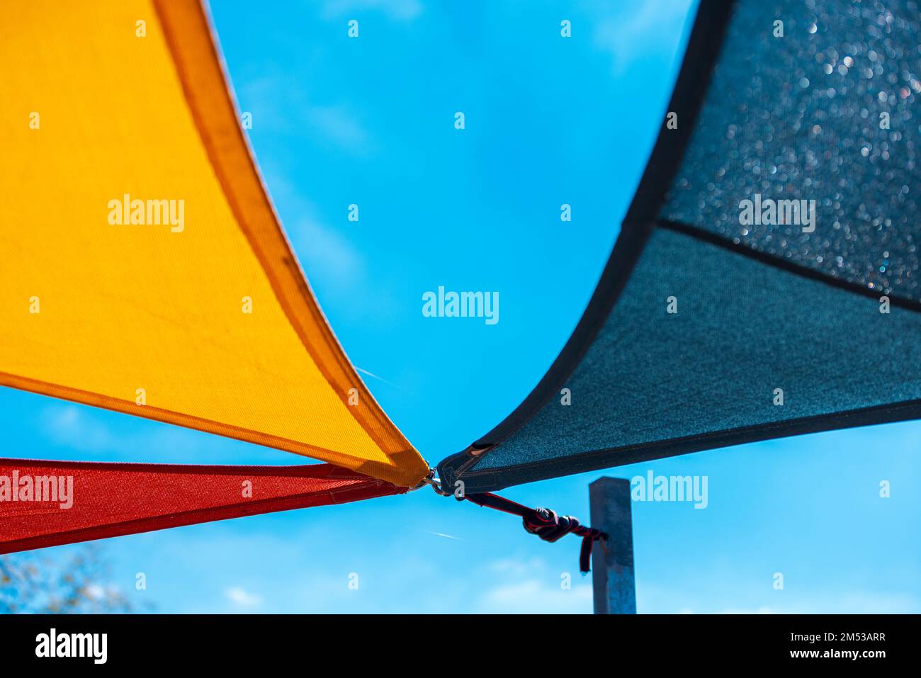 A low angle shot of colorful shade nets under the bright blue sky on a ...