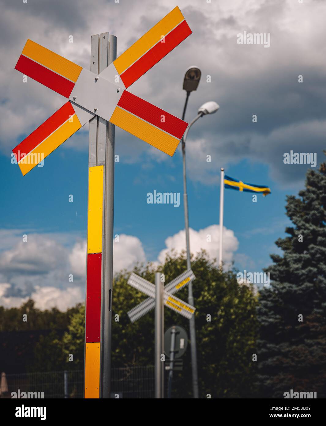 A closeup of an red and yellow railroad crossing sign against a cloudy ...