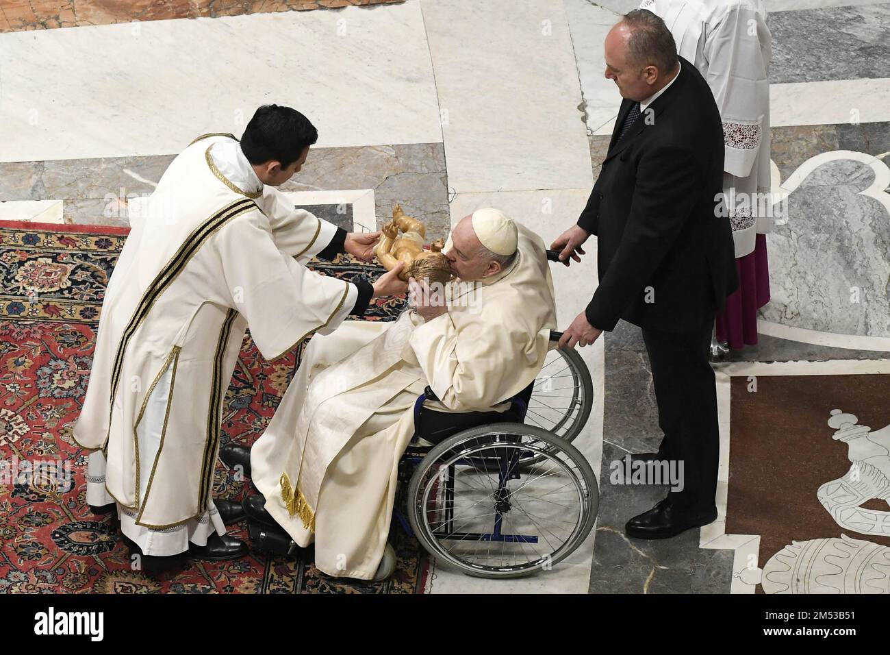 Pope Francis, in a wheel chair, kisses a figurine of baby Jesus during ...
