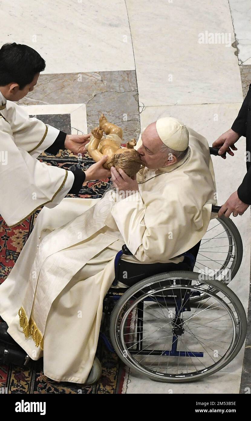 Pope Francis, in a wheel chair, kisses a figurine of baby Jesus during ...