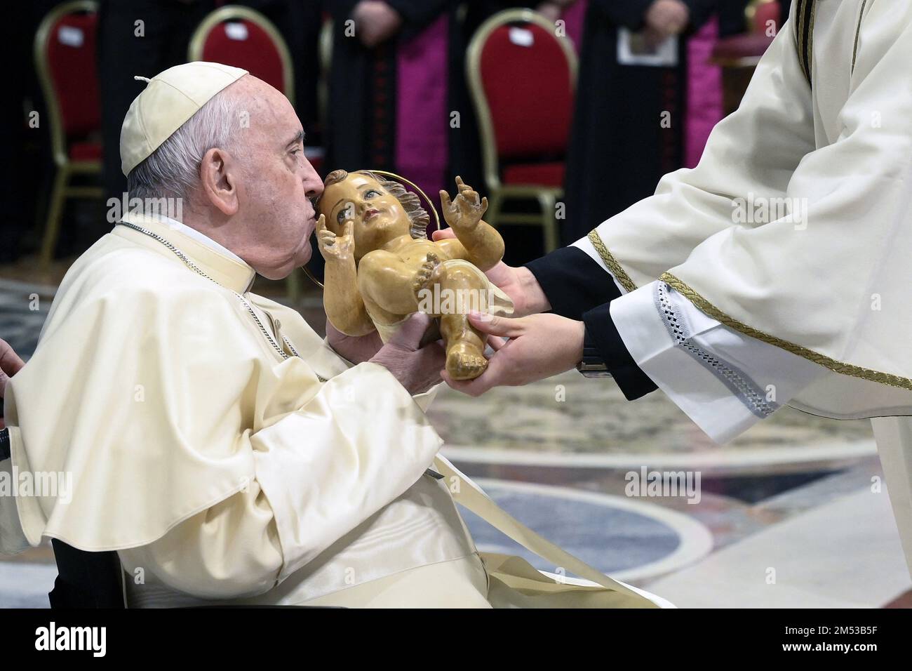 Pope Francis, in a wheel chair, kisses a figurine of baby Jesus during ...