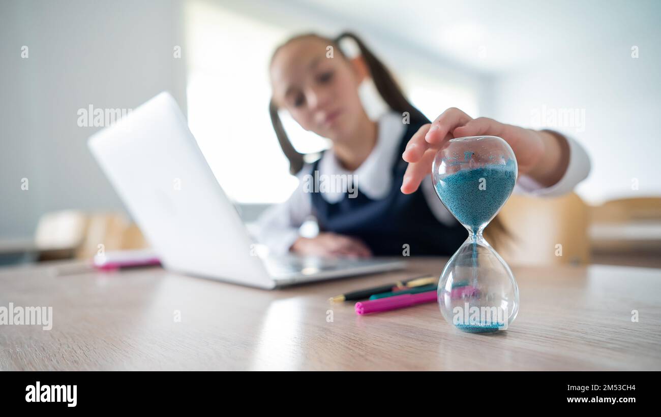 Caucasian girl sits at a desk at school and studies at a laptop. The ...