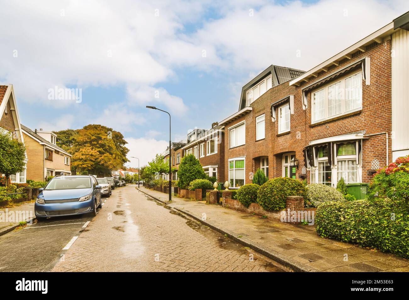 a street with cars parked on the side and houses in the back, all ...