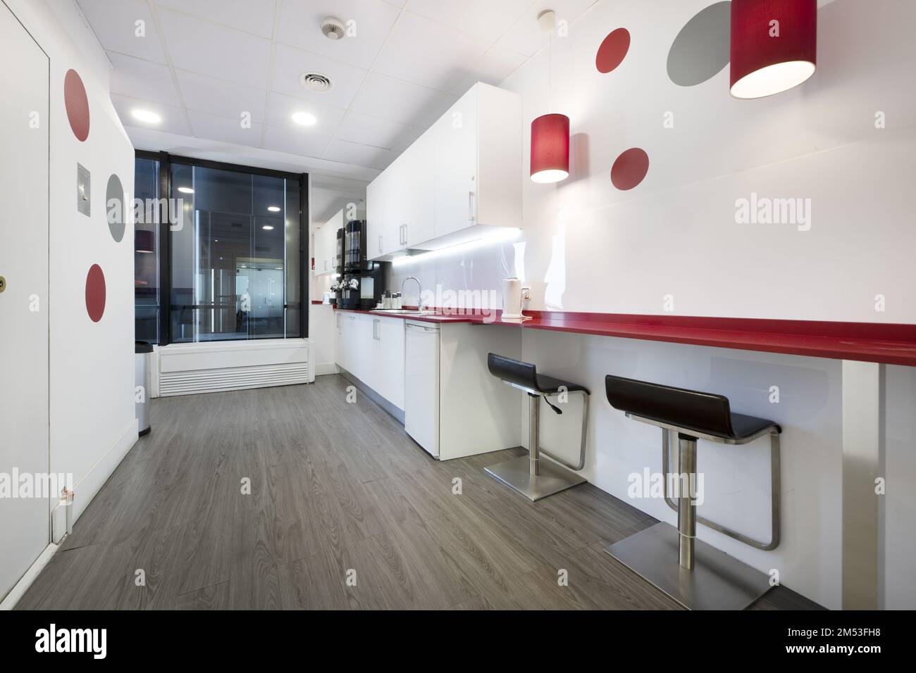 Kitchen of a coworking office with a red countertop and white cabinets ...
