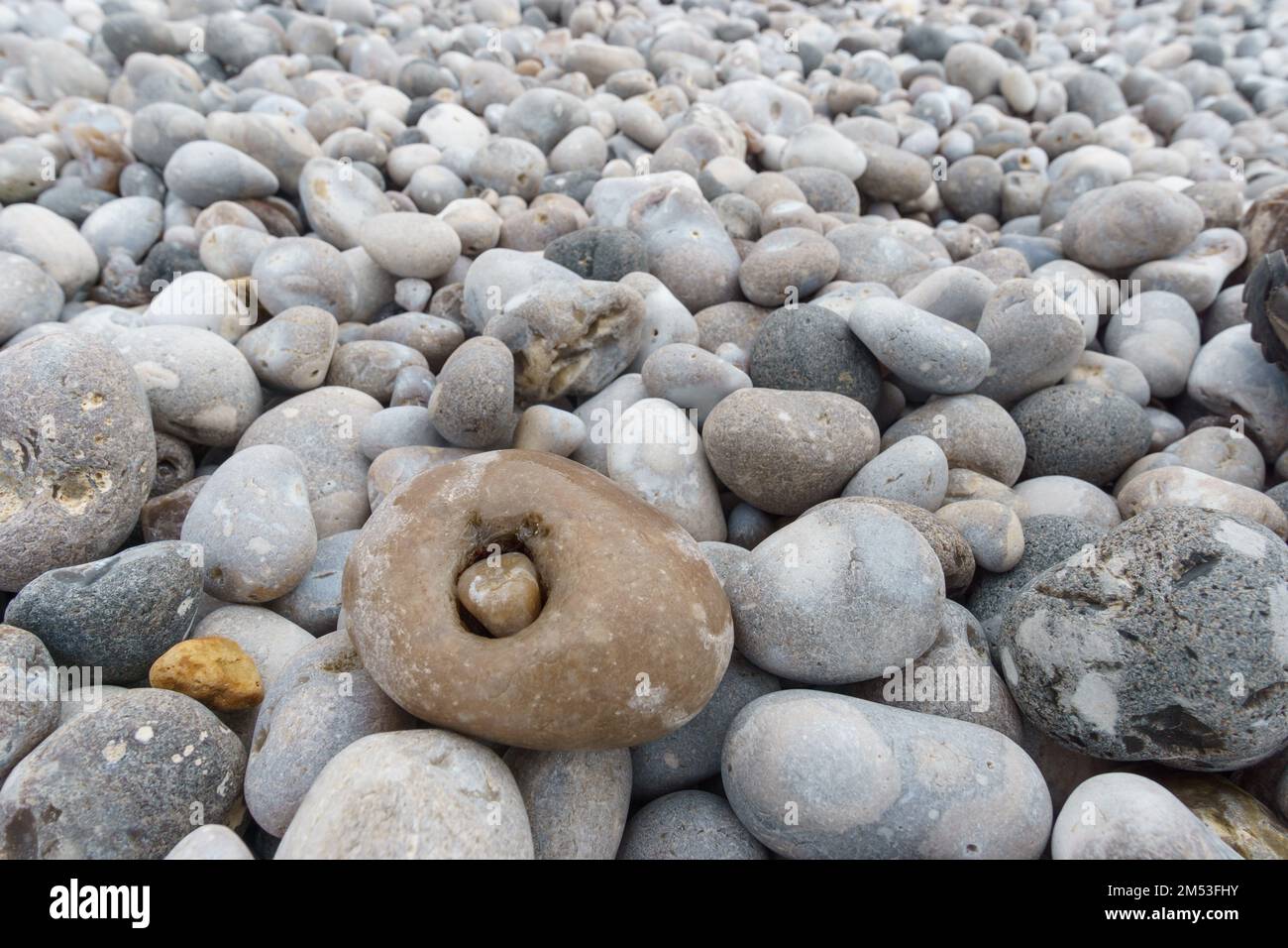 Sea pebble stones background with small stone enclosed inside a bigger ...