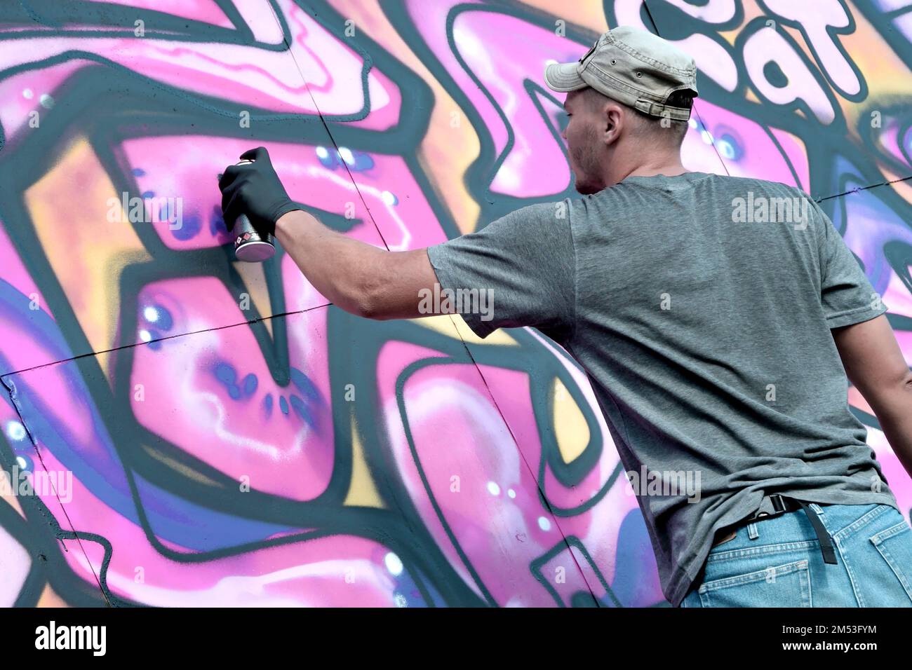 Young caucasian male graffiti artist drawing big street art painting in ...