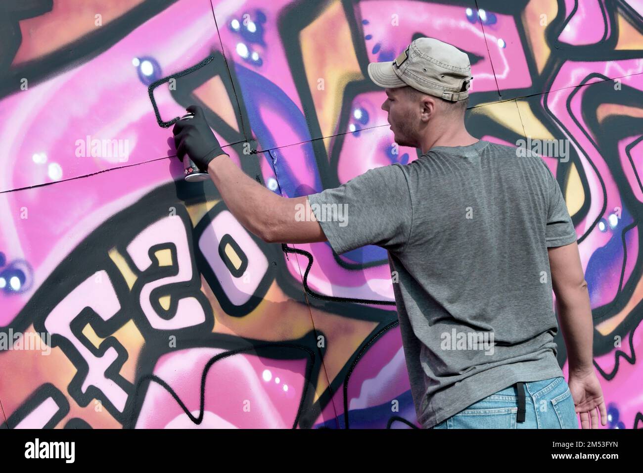 Young caucasian male graffiti artist drawing big street art painting in ...