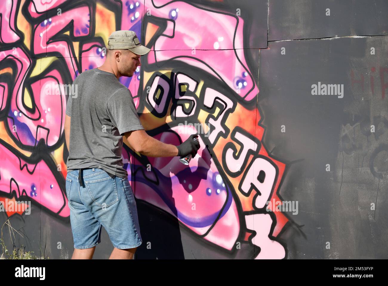 Young caucasian male graffiti artist drawing big street art painting in ...