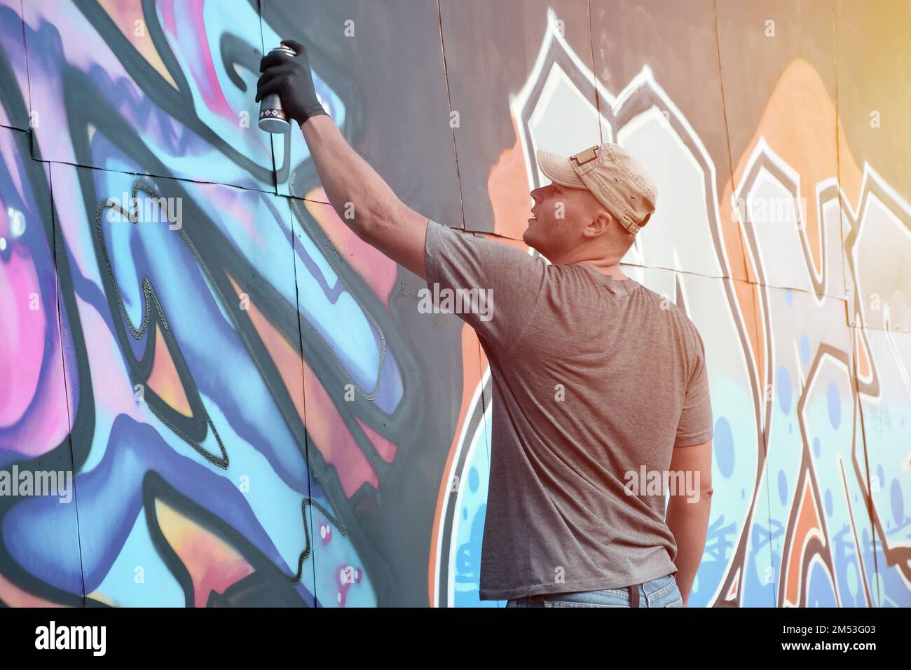 Young caucasian male graffiti artist drawing big street art painting in ...