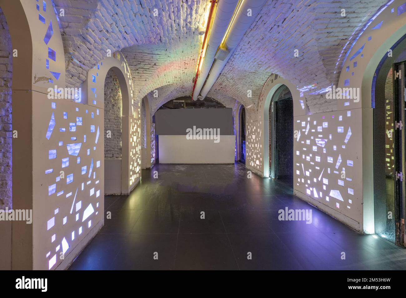 Empty room of a night club with led lights and white painted brick ...