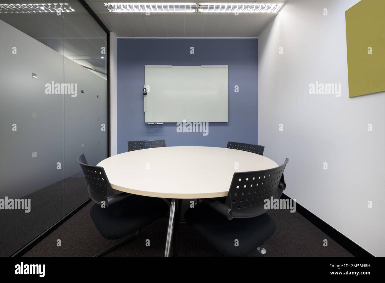Small boardroom with white round circular table and whiteboard with ...