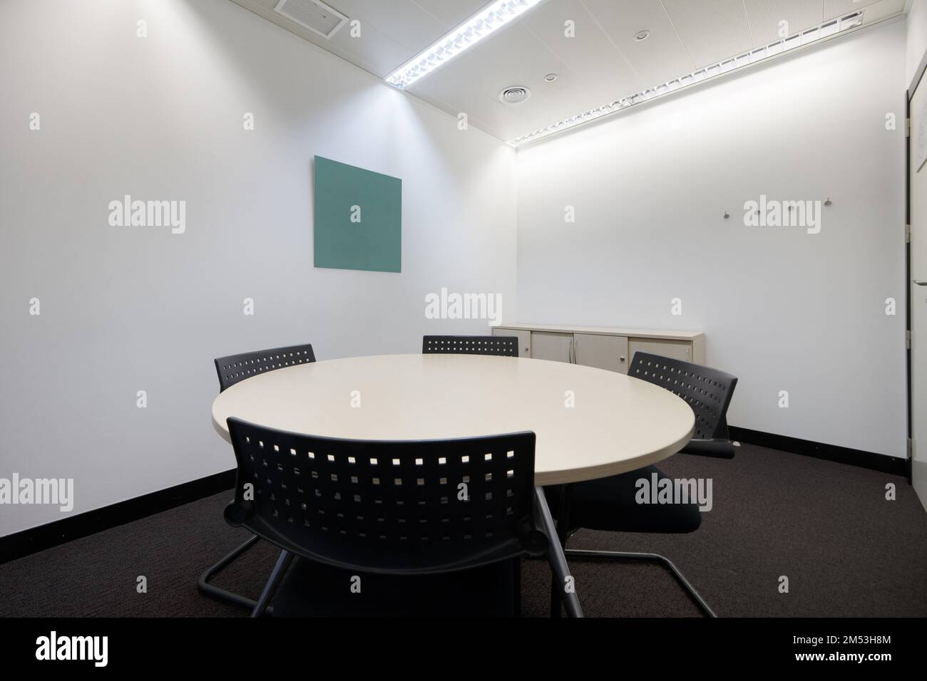 Small meeting room with white round circular table and whiteboard with ...