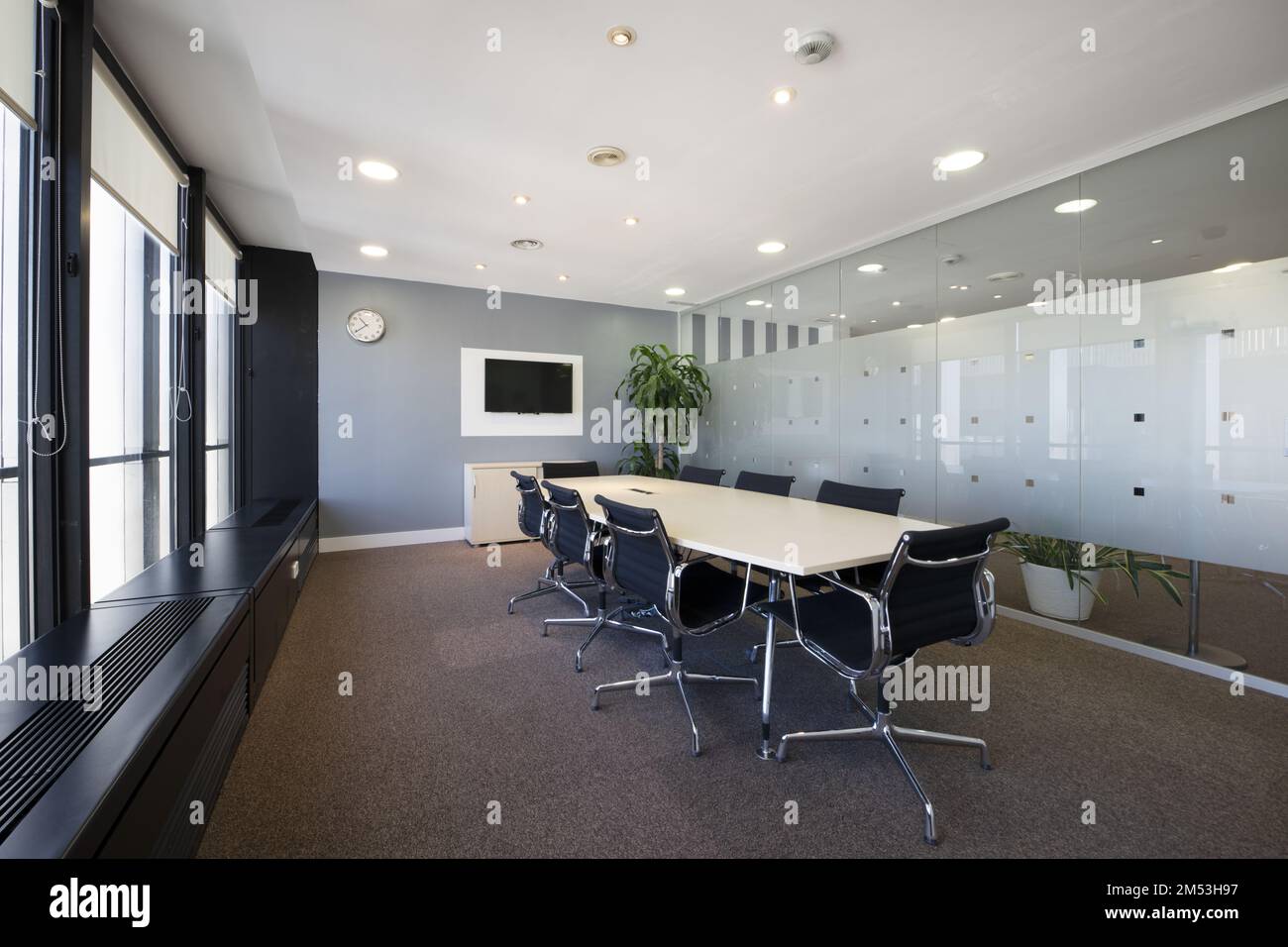 Boardroom with long wooden table with black swivel chairs and wall of ...