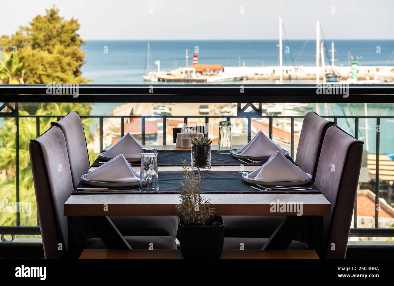 Dinner setting at harborside restaurant with sea harbor and yachts in ...