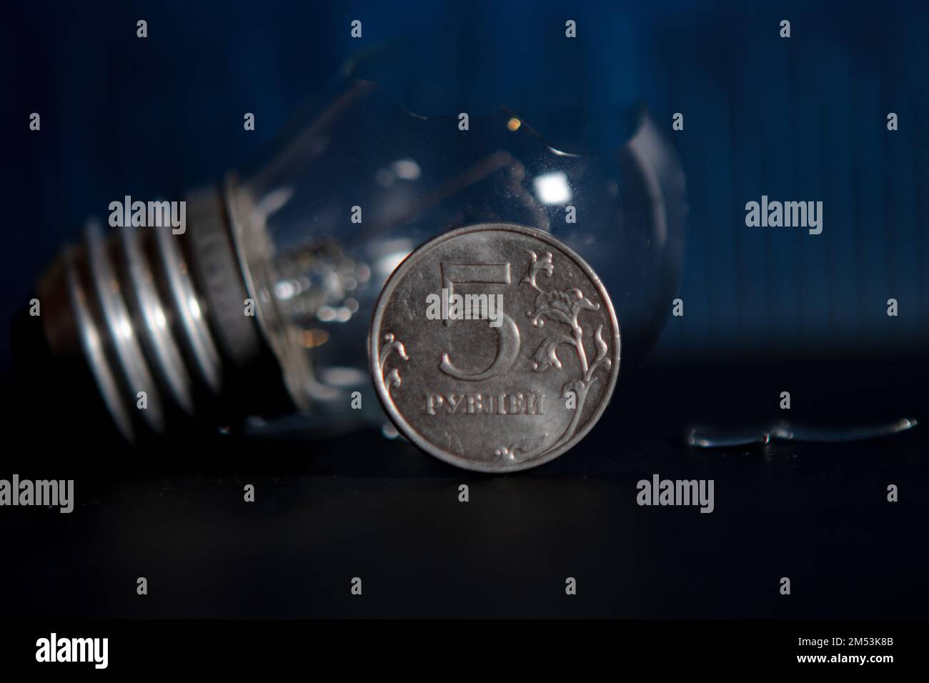 Broken light bulb with pieces of glass and 5 Russian 5 ruble coin ...