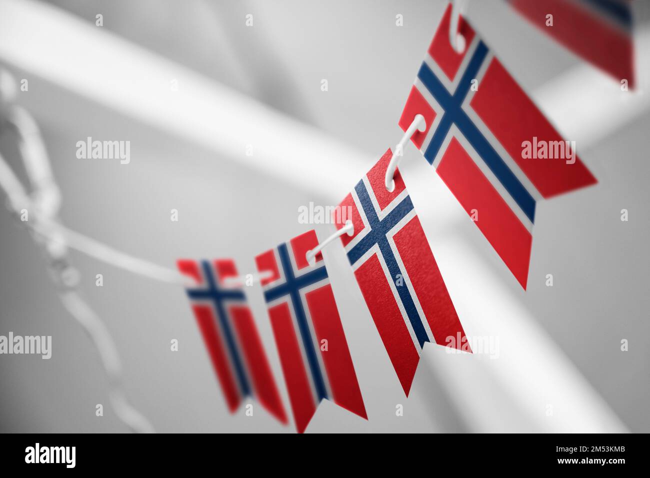 A garland of Norway national flags on an abstract blurred background ...