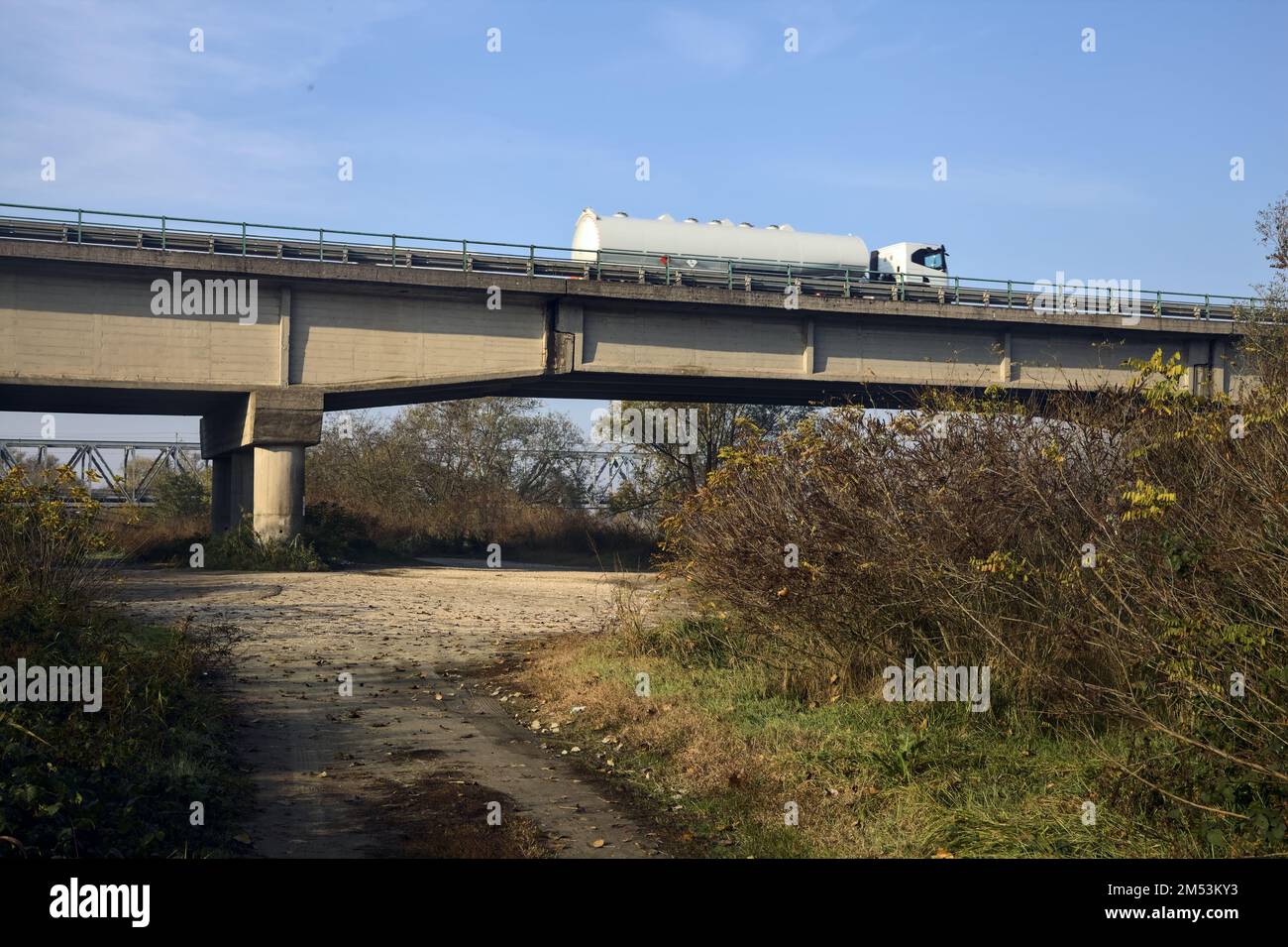 Bridge with a truck passing by on it seen from dirt path below Stock ...