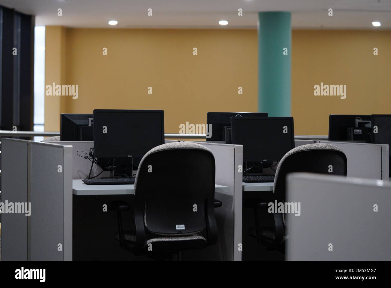 grey computer desks with black and fray chairs at the office building ...