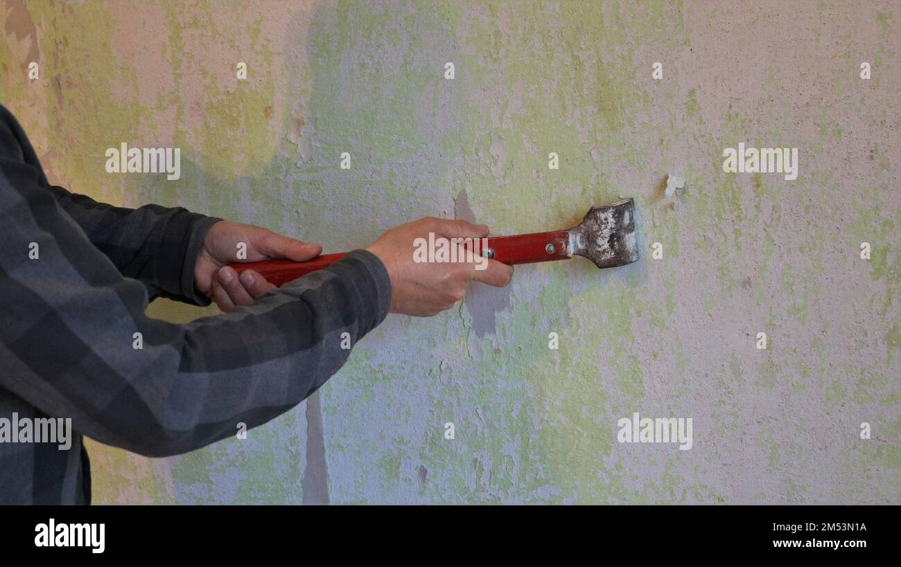 scraping off the remains of glue, wallpaper and plaster from the wall ...