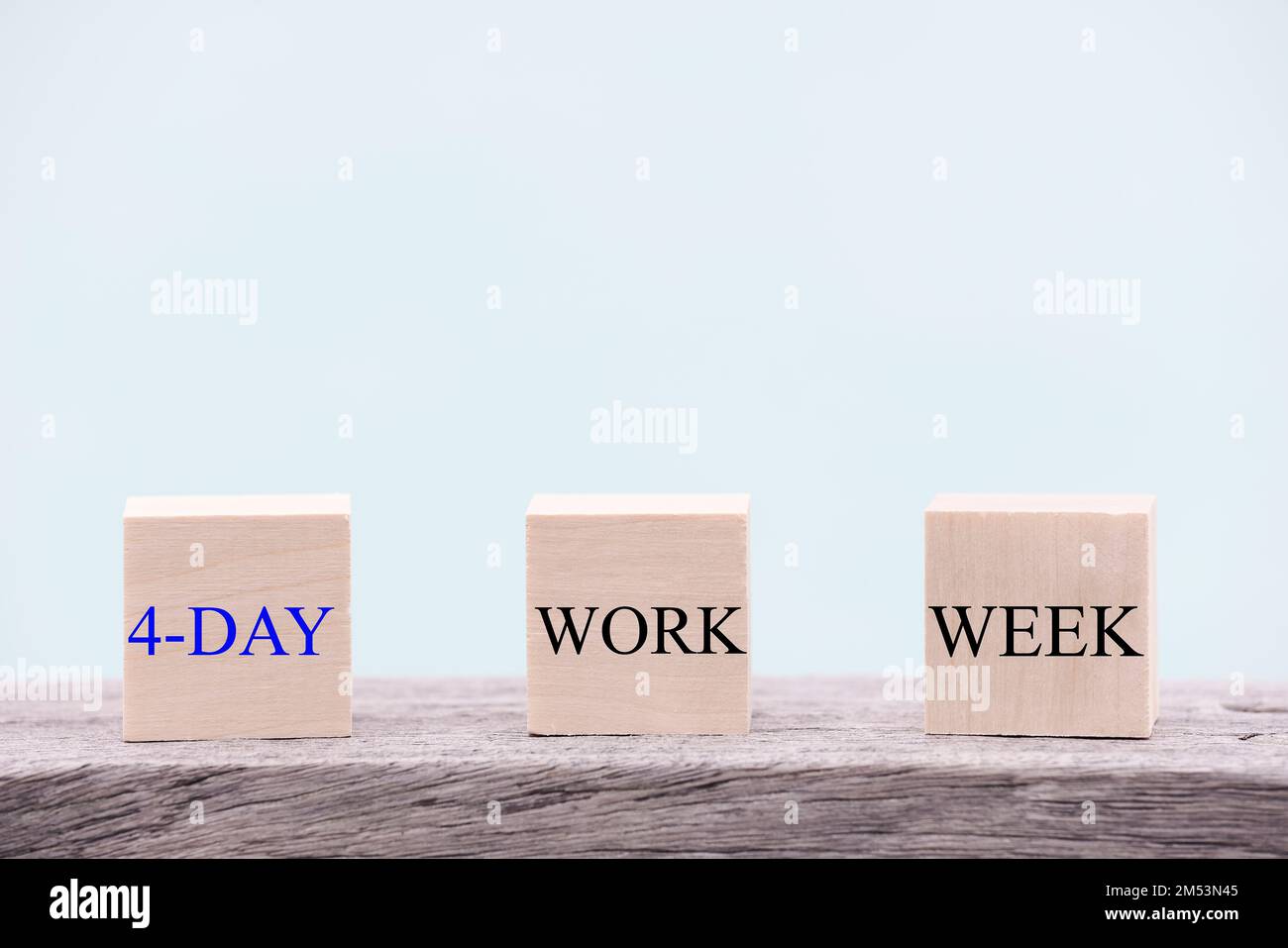 4 day working week words on wooden cube on blue background. reducing ...