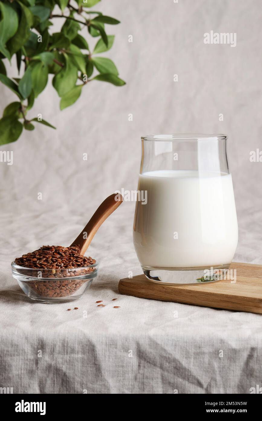 flax seed milk in glass on textile background with plant. copy space ...