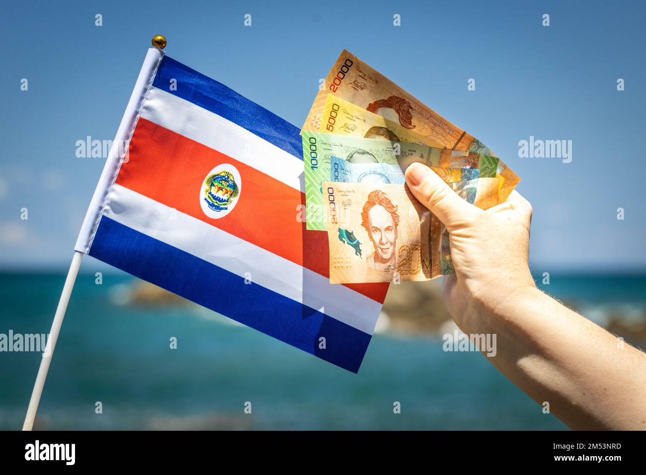 A woman holds money in her hand and the flag of Costa Rica against the ...