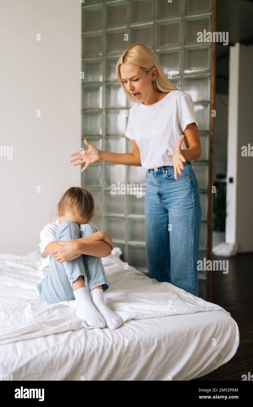 Vertical shot of sad crying little girl covering face with palm while ...