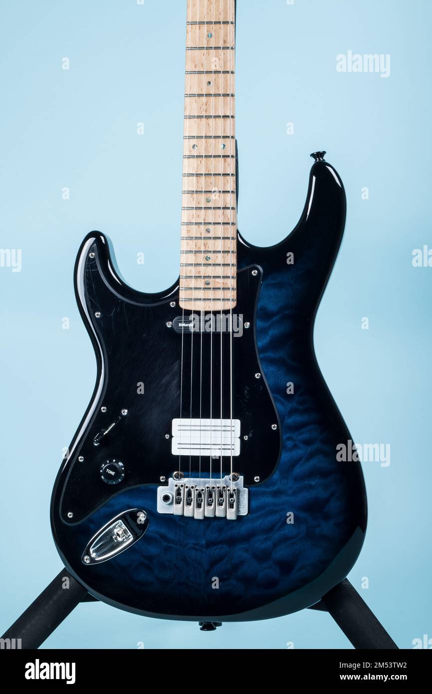 A vertical shot of black and dark blue electric guitar on a stand on ...