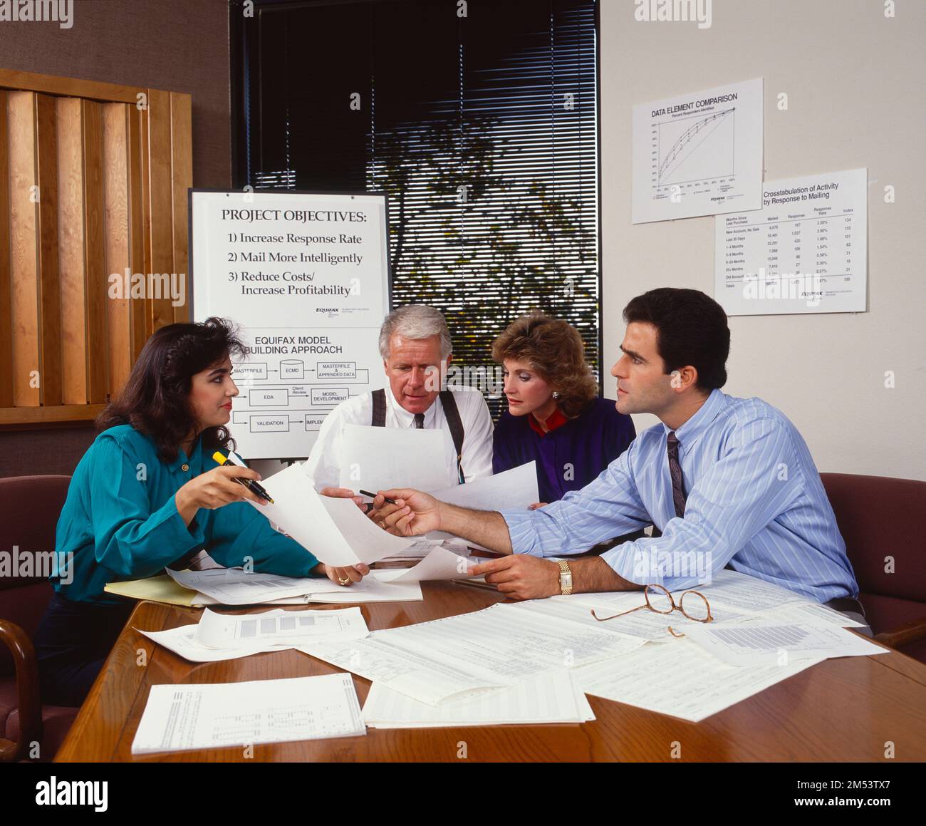 Businessmen and business women sitting around conference table ...