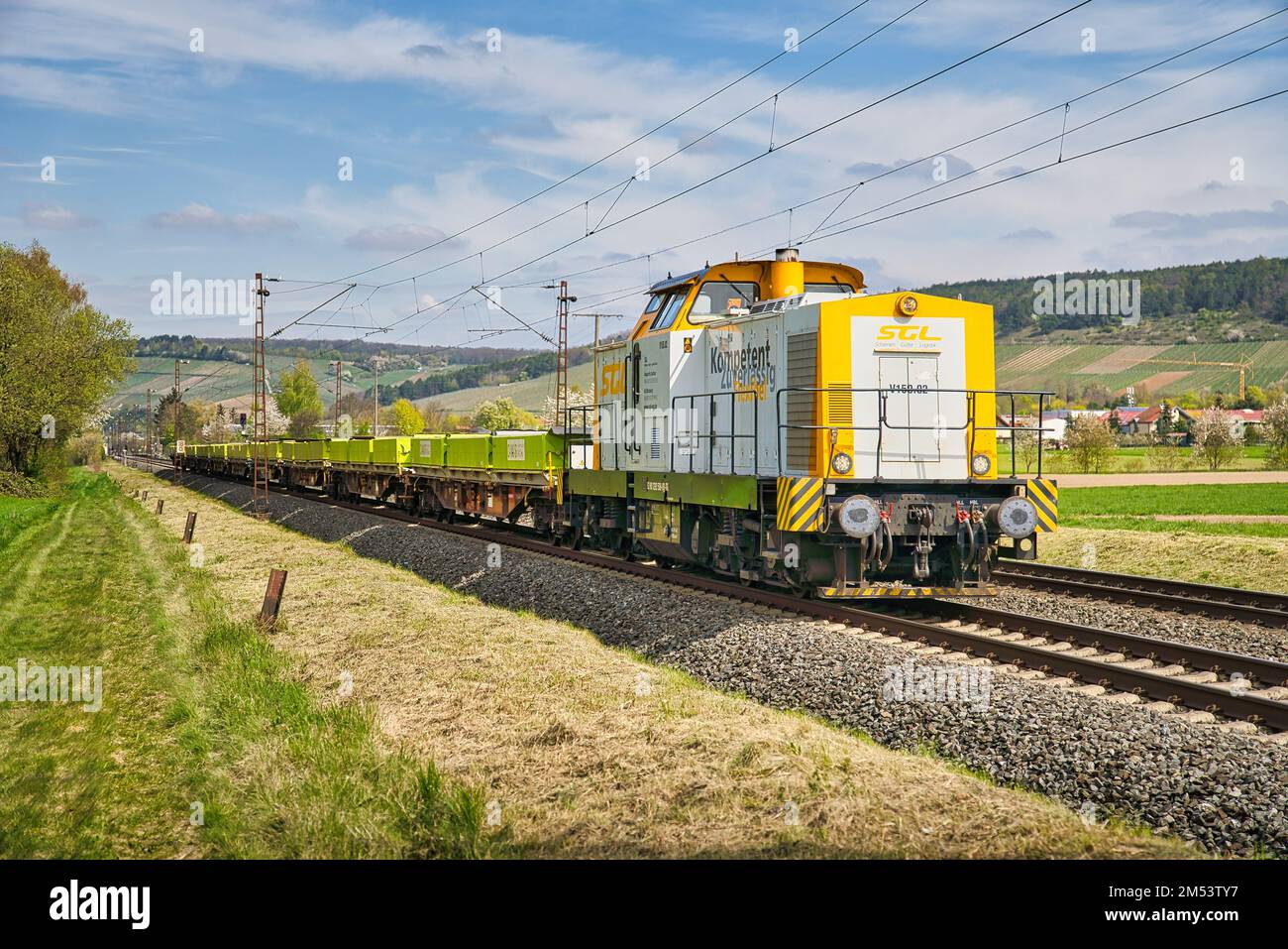 A yellow freight train on the railway with a field in the background ...