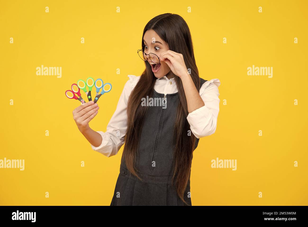 Teenage school girl with scissors, isolated on yellow background. Child ...
