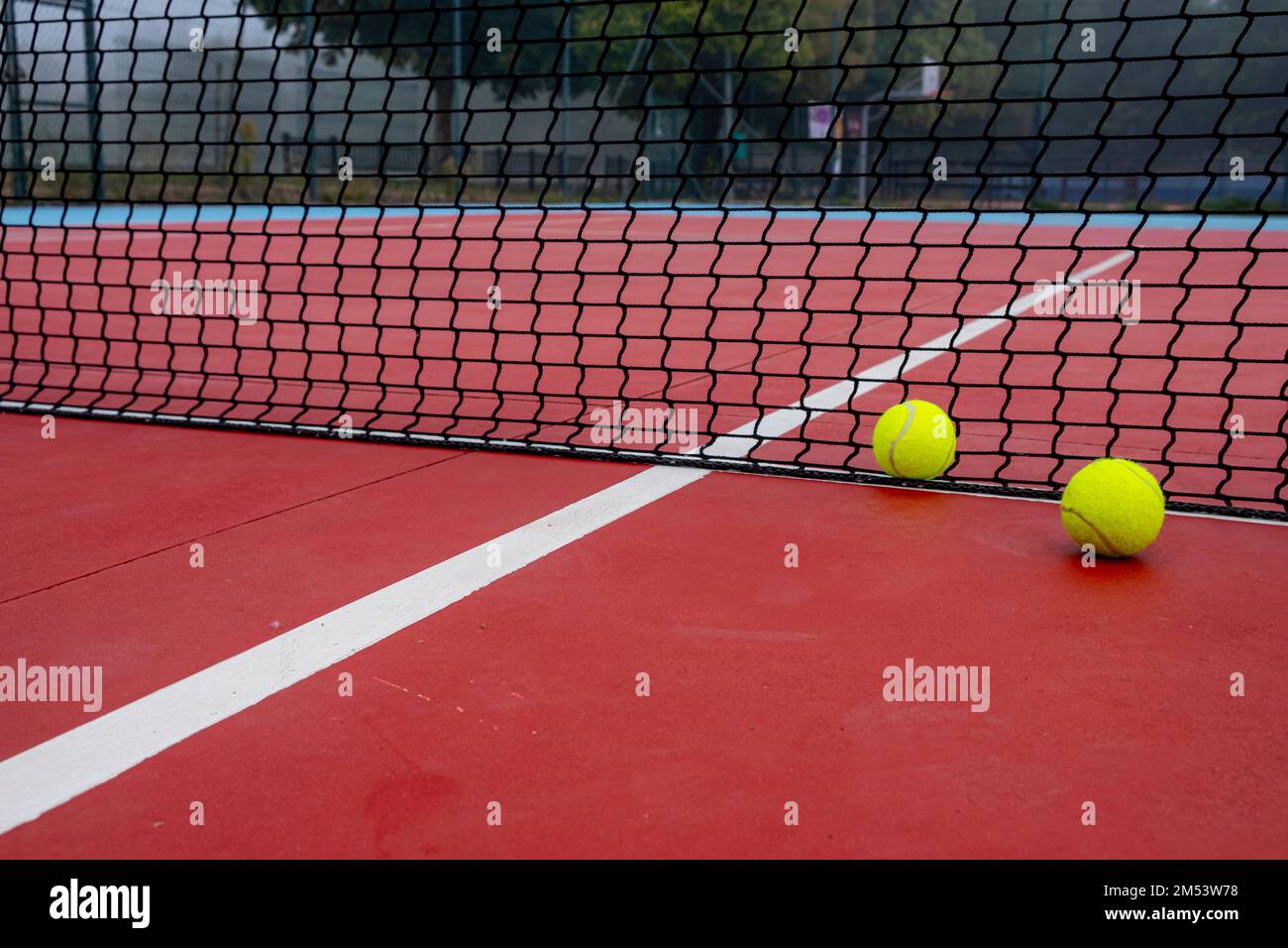 The two tennis balls resting by the net and court lines on a red ...