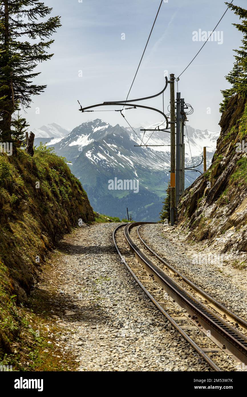 A vertical of railroad tracks leading to an Alpine mountain skyline in ...