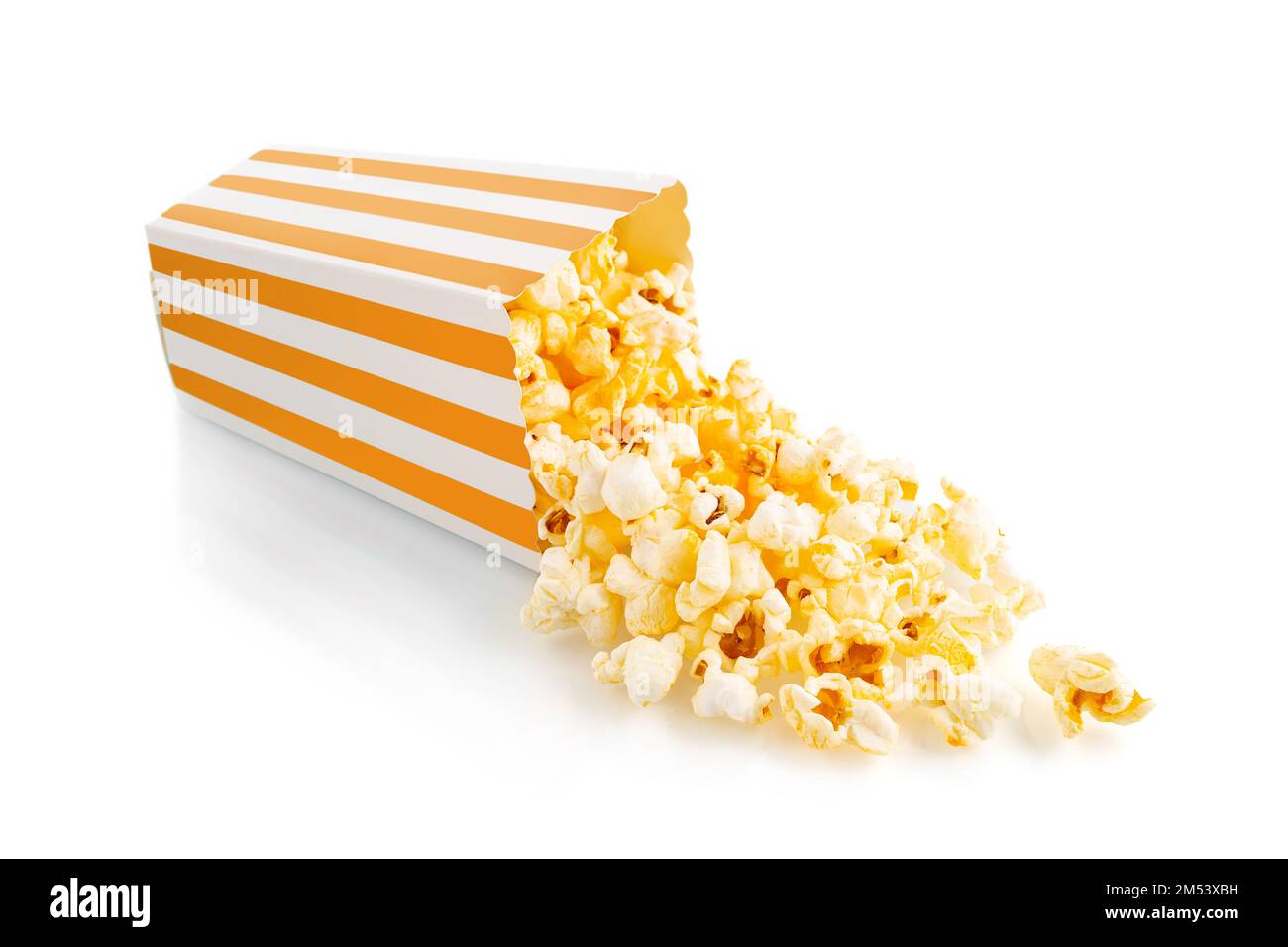 Tasty cheese popcorn falling out of a yellow striped carton bucket ...