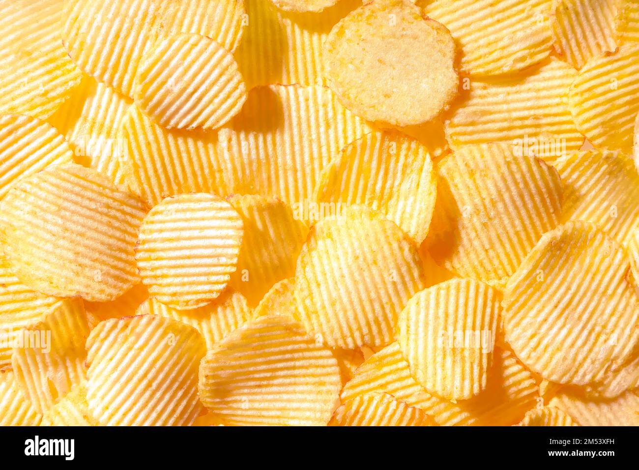 Yellow crispy ridged potato chips close up. Food background, banner ...