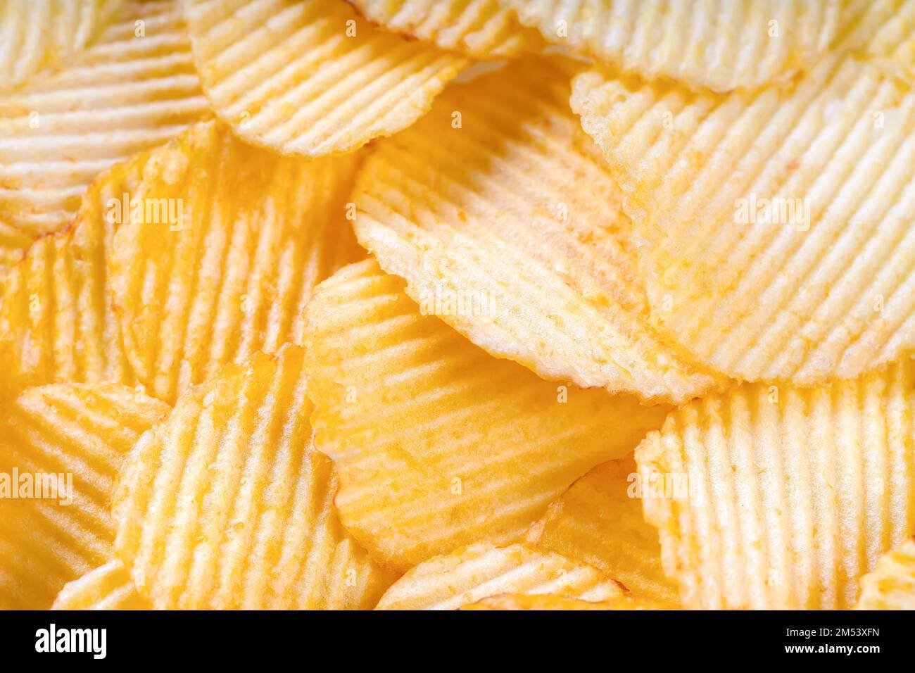 Yellow crispy ridged potato chips close up. Food background, banner ...