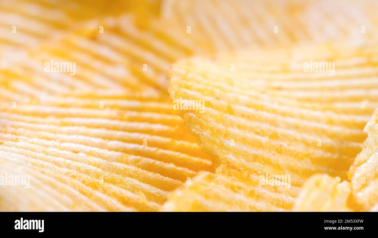 Yellow crispy ridged potato chips close up. Food background, banner ...